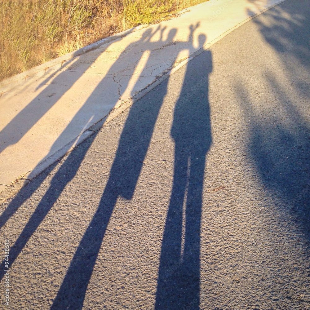 long shadows of four people with their arms in the air waving. Stock ...