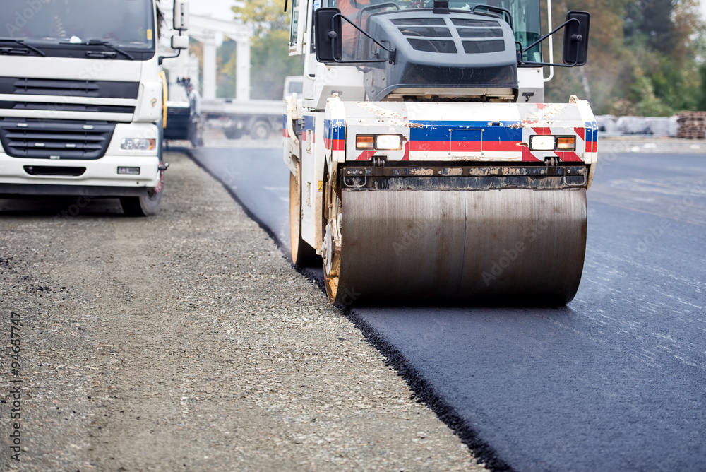 Road works, asphalting and laying fresh bitumen during construction ...