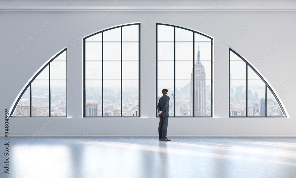 Rear view of a person in formal suit who is looking out the window in a ...