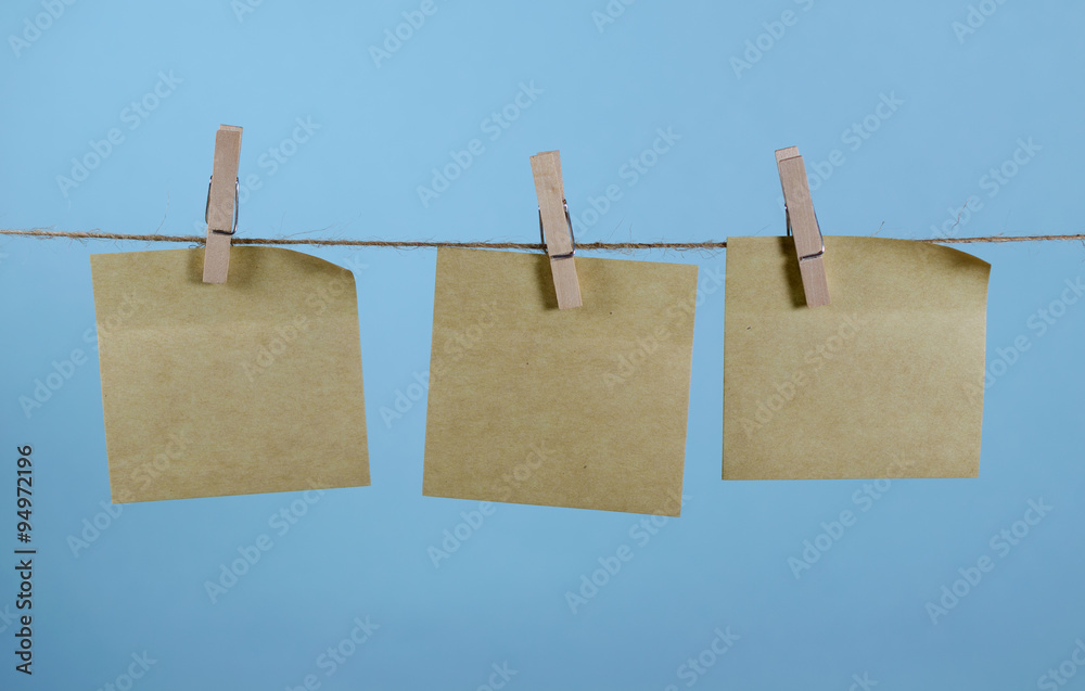 Empty old paper notes hanging on a rope attached with pegs on a blue ...