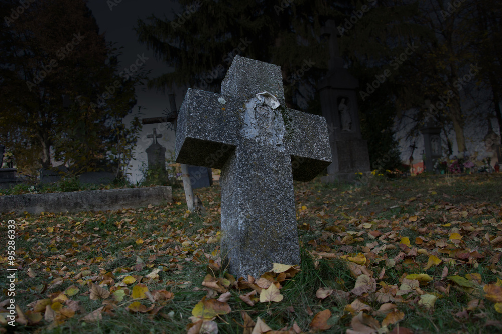 Spooky leaning cross tomb stones in a dark autumn scene at night. Old ...