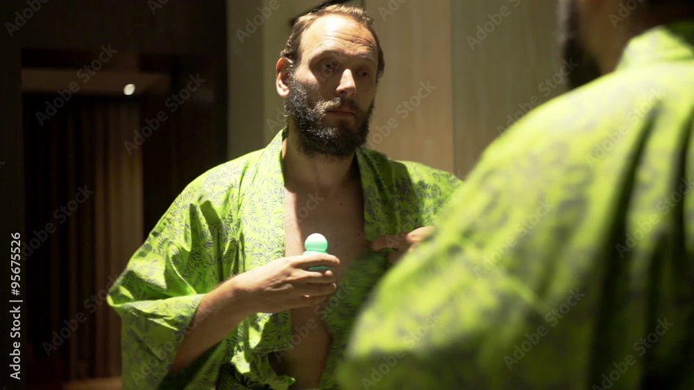 Young man in bathrobe applying antiperspirant in bathroom Stock Video | Adobe Stock