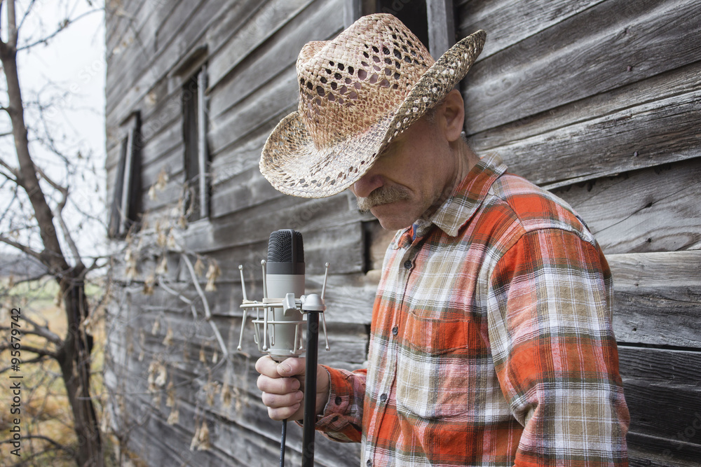 horizontal image of a cowboy singer wearing a cowboy hat and checkered ...