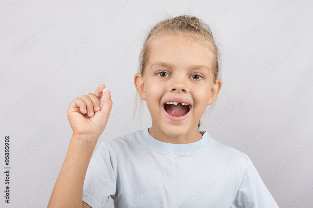 Girl holds the tooth in his hand and his mouth open showing a hole ...