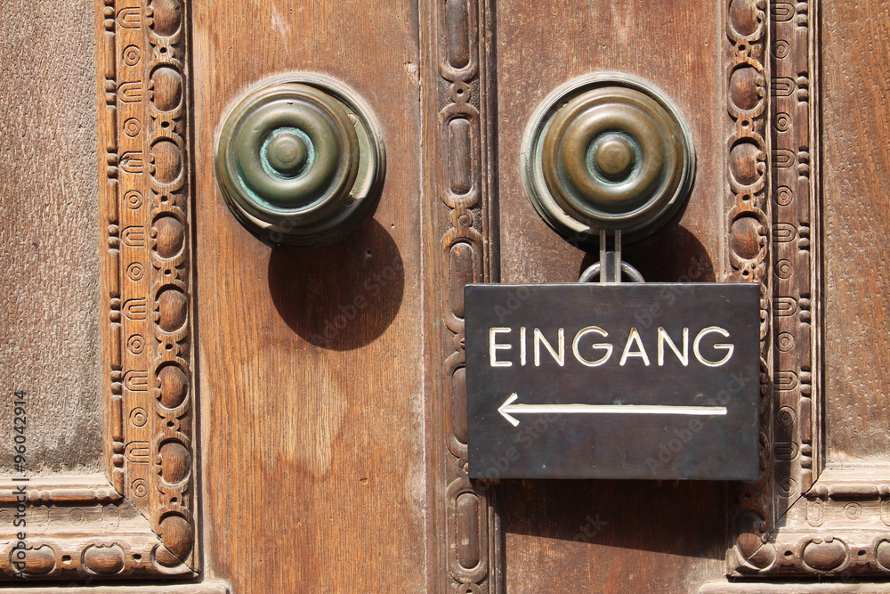 Historical wooden door with a direction sign "Entrance" (Eingang) in ...