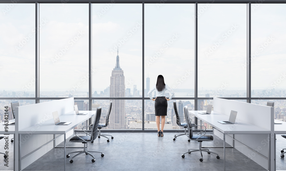Rear view of a brunette who is looking out the window in the modern ...