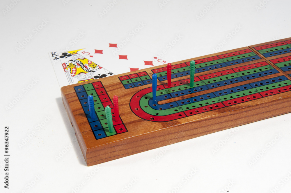 Cribbage board with red, green and blue pegs against a white background ...