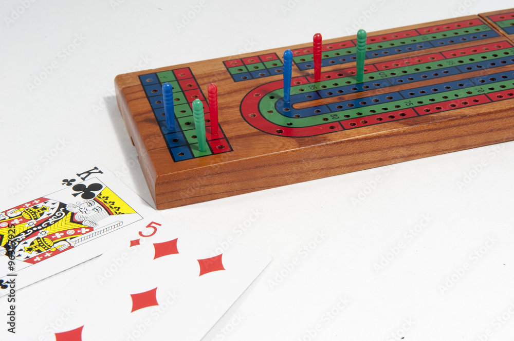 Cribbage board with red, green and blue pegs against a white background ...