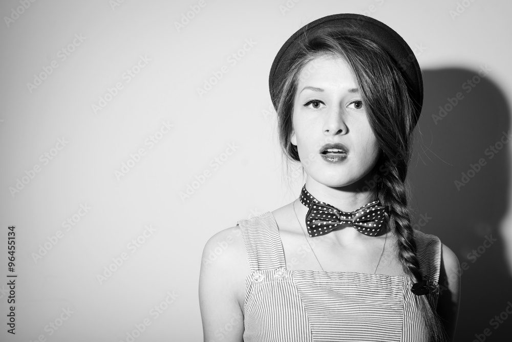 Beautiful girl in hat and bow tie looks surprised. Black and white ...