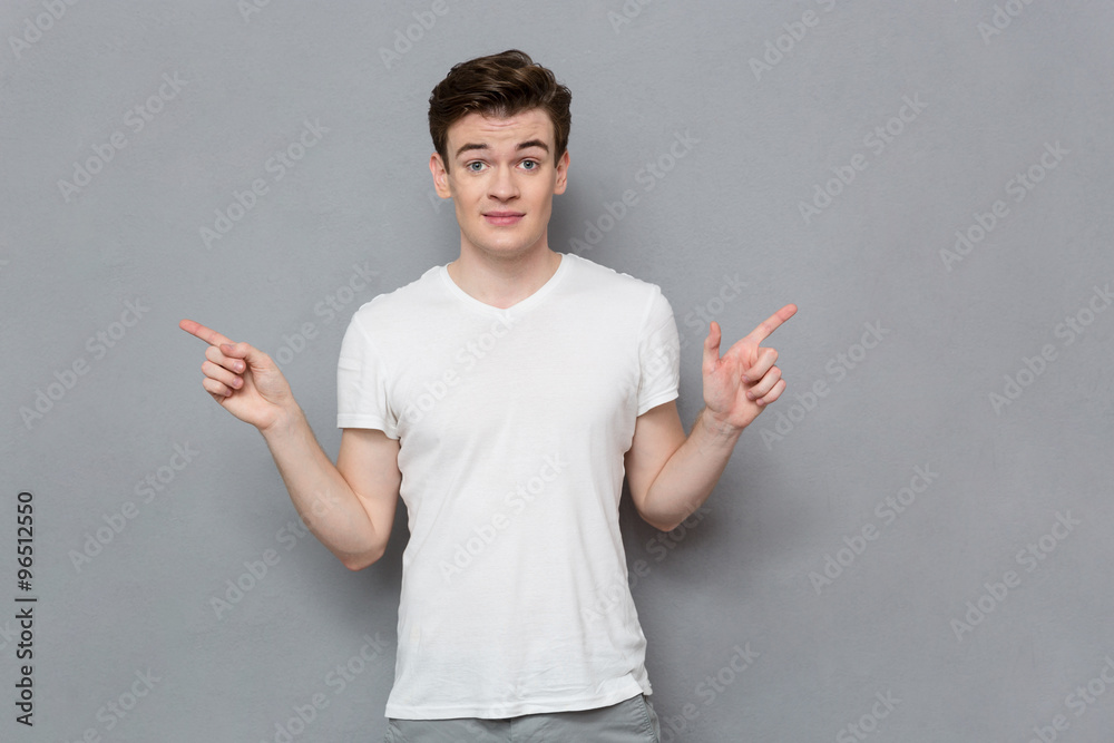 Confused young man showing fingers in different directions Stock Photo ...
