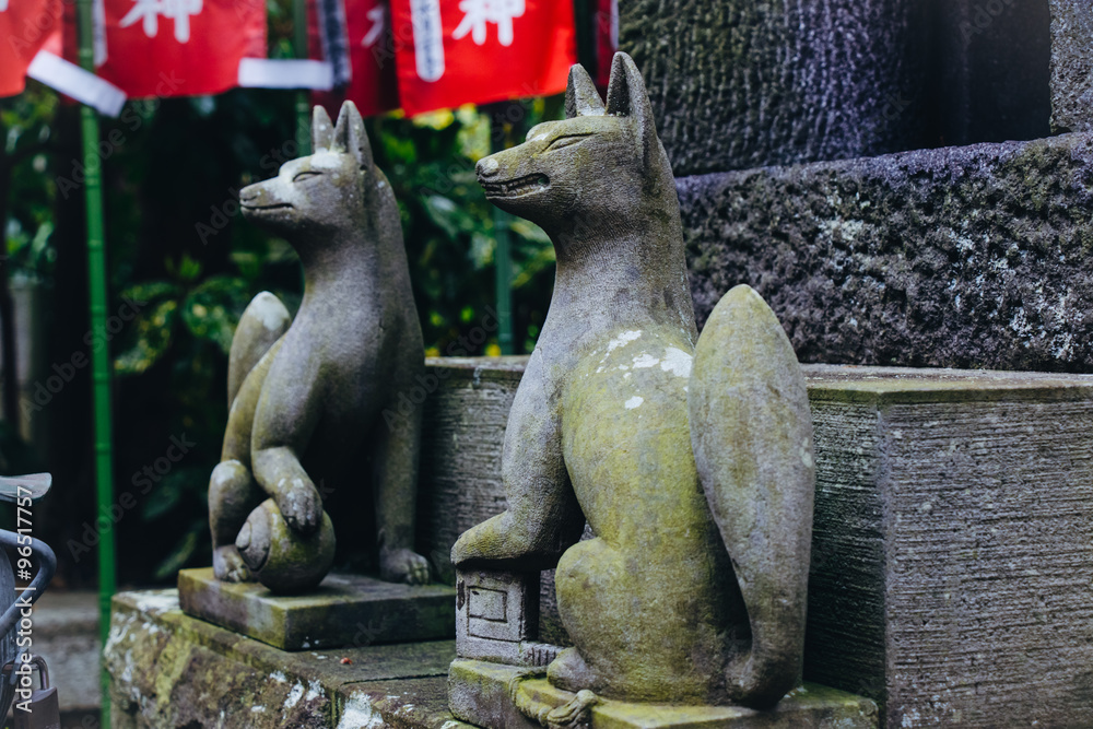 A pair of stone fox sit in front of a small shrine in Japan. Stock ...