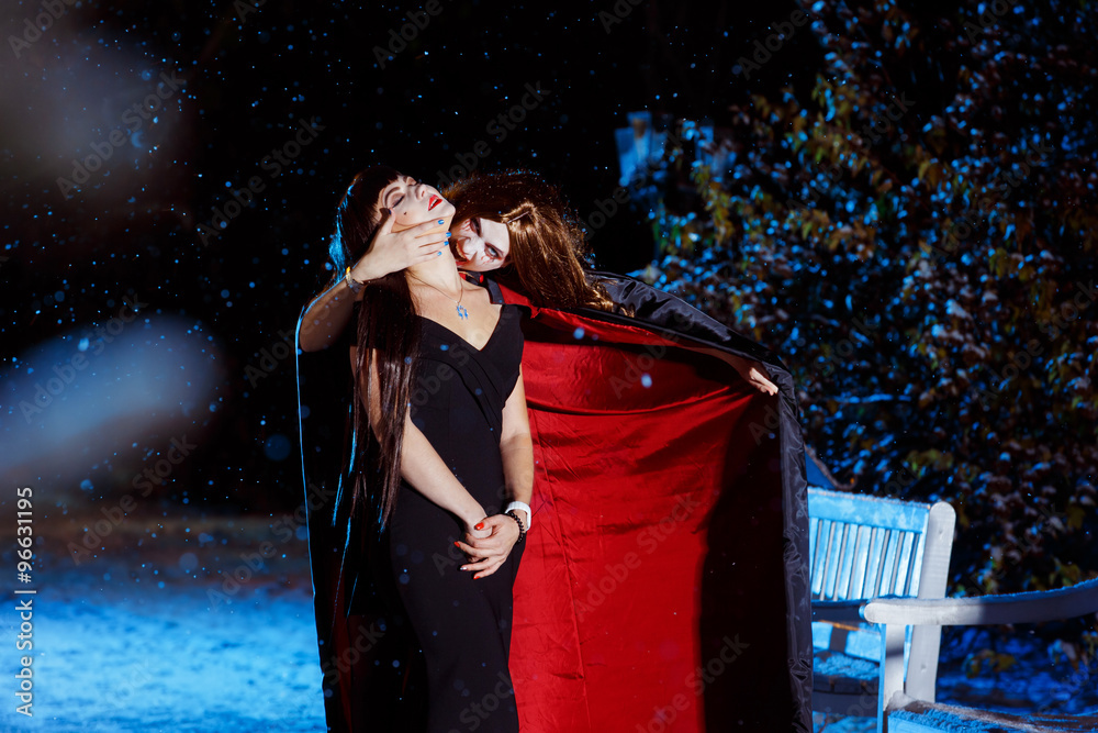 Beautiful female vampire in long pallium is biting her victim Stock ...