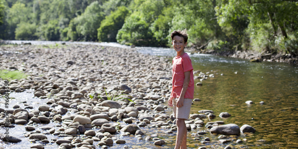 Niño con camiseta roja sonriendo en el río Stock Photo | Adobe Stock