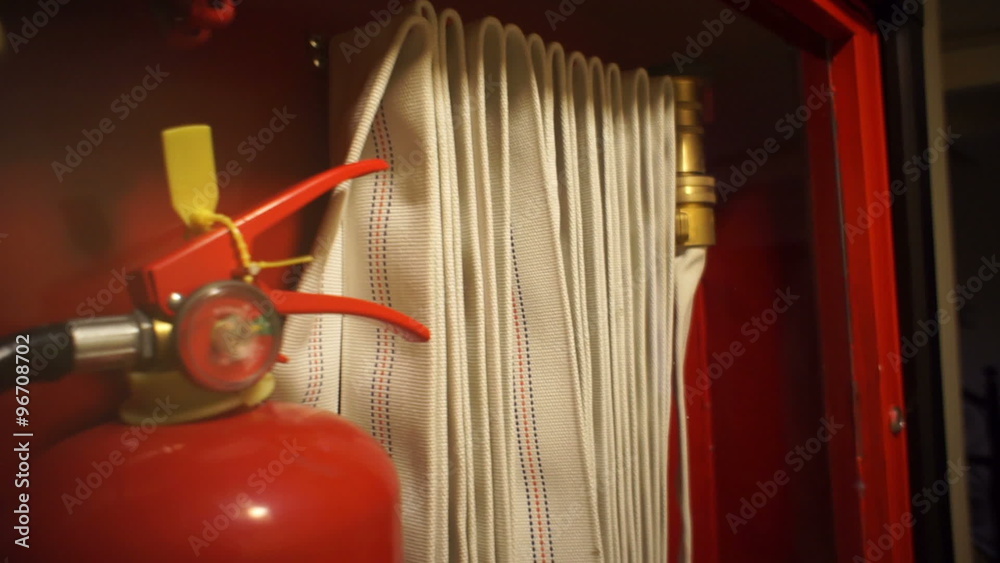Close up handheld shot of an emergency fire extinguisher and fire hose ...