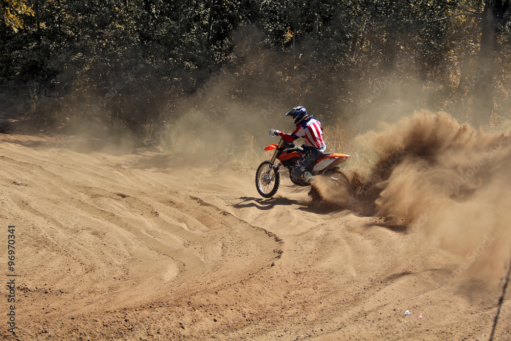 Motocross racer moves along sandy parapet turning track per motorcycle ...