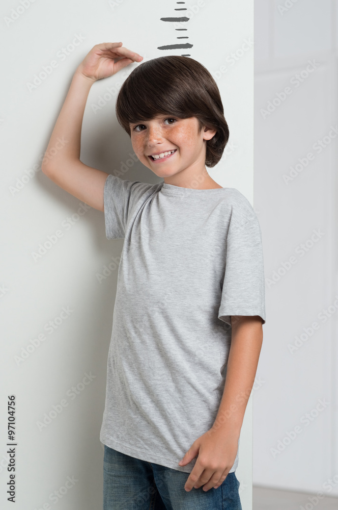 Boy growing tall and measuring himself Photos | Adobe Stock