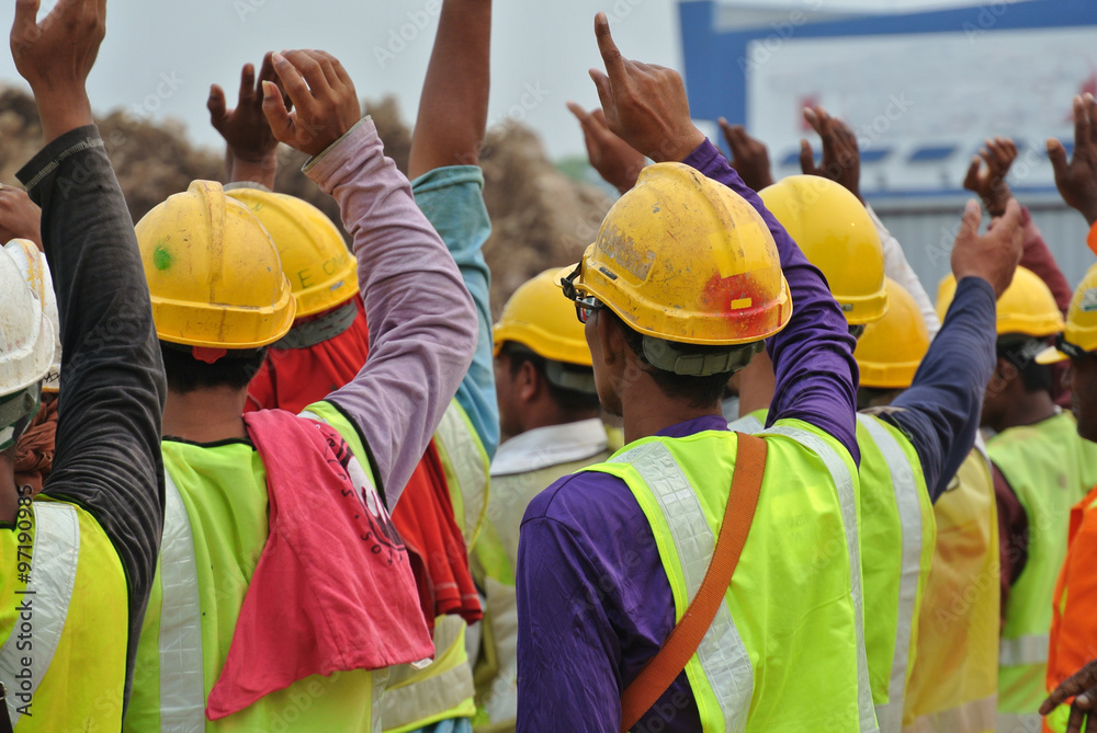 Group of construction workers raise their hand and assemble at the open ...