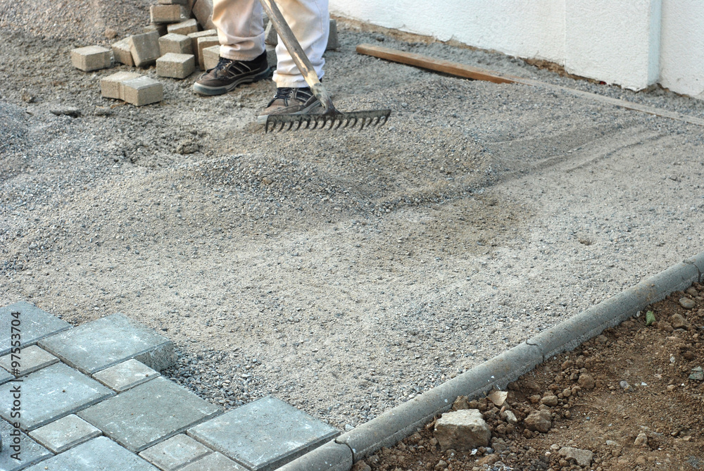 Construction site worker leveling the sand during installing concrete ...