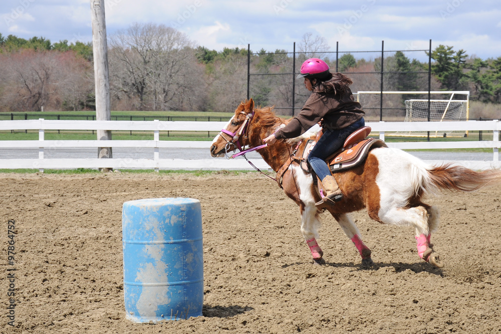 Teenage girl barrel racing; A young teenage girl turns around a barrel ...