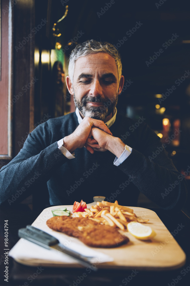Smiling man in restaurant having Wiener Schnitzel with French fries ...