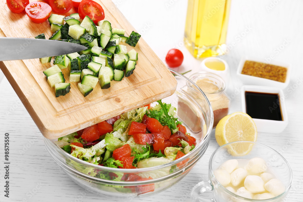 Female hands adding vegetables into bowl with salad, close-up Stock ...