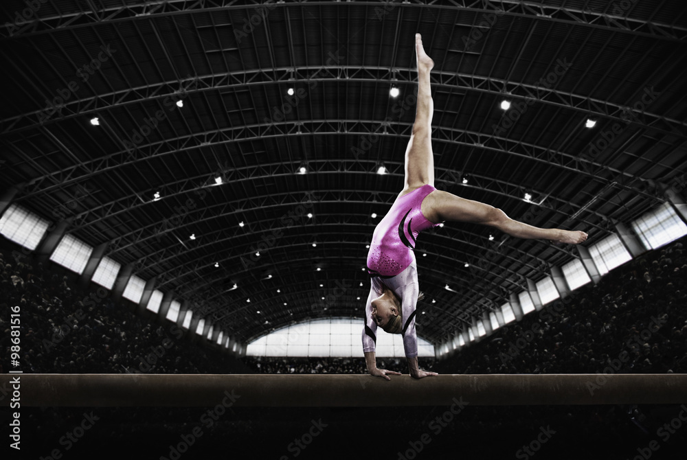 A gymnast on the beam performing a routine Stock Photo | Adobe Stock