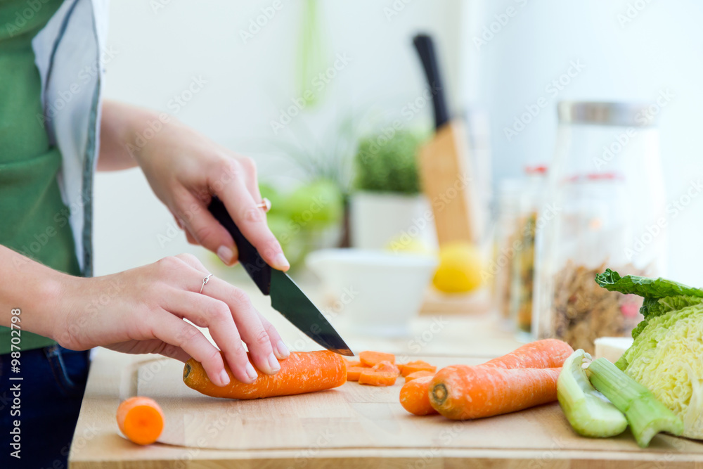 Pretty young woman cutting vegetables in the kitchen. Stock Photo ...