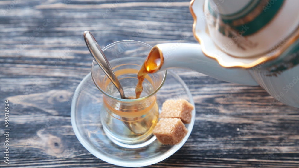 Pouring tea into a cup on a wooden table Stock Video | Adobe Stock