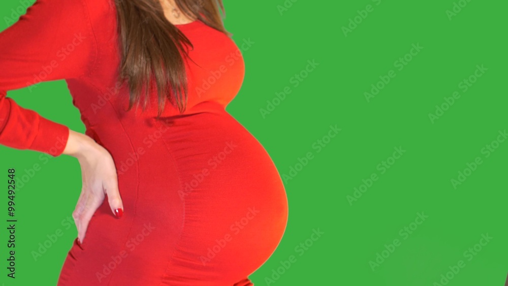 pregnant woman in red dress turns to show off huge belly- green screen ...