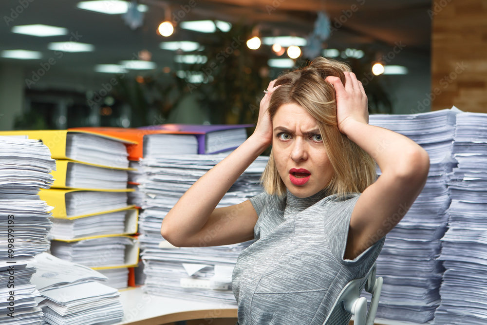 Office businesswoman at her desk full of documents, showing an ...
