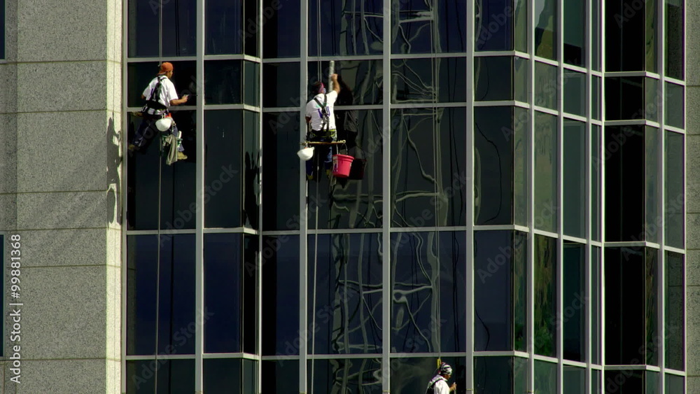 Vidéo Stock Men rappelling and washing windows at a construction site ...
