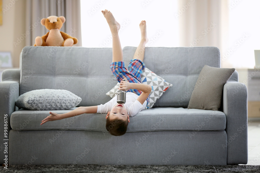 Little boy singing with a microphone on a sofa at home Stock Photo ...