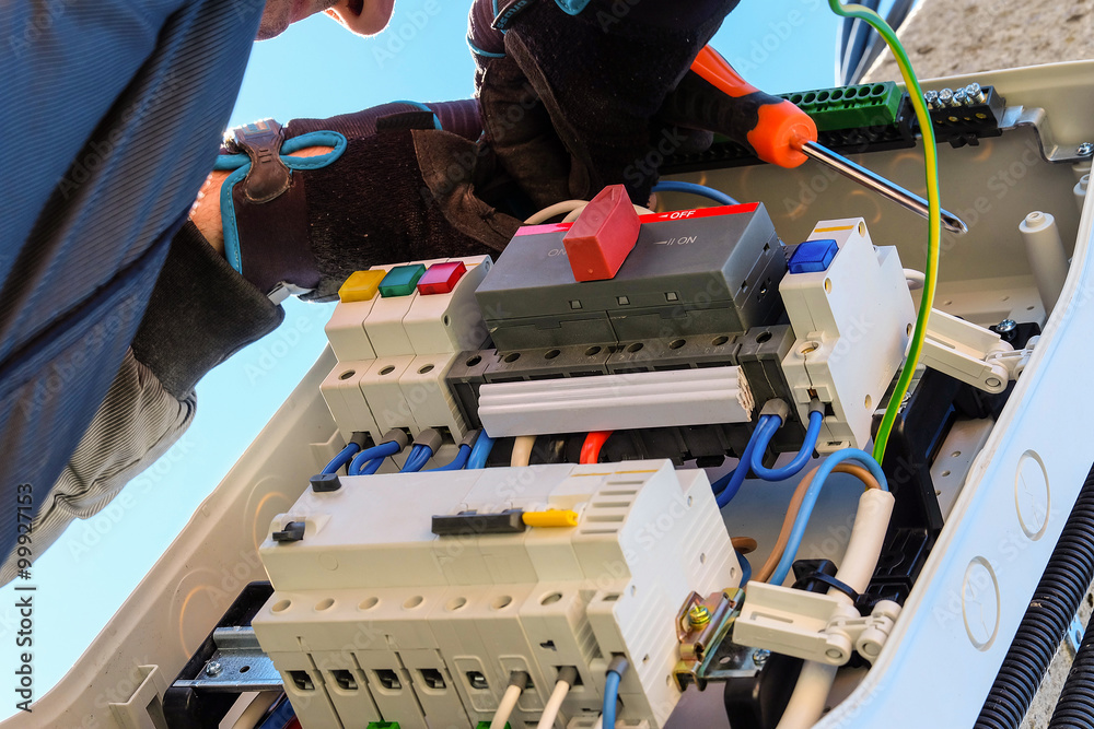 Hands of an electrician with screwdriver at an electrical control panel ...