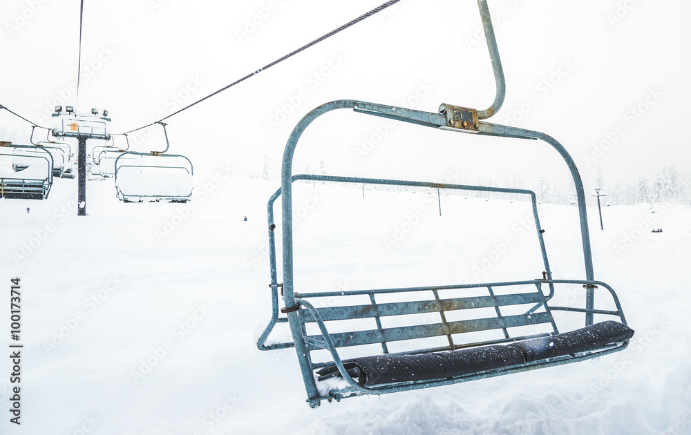 scene of close up ski lift with seats going over the snow mountain ...