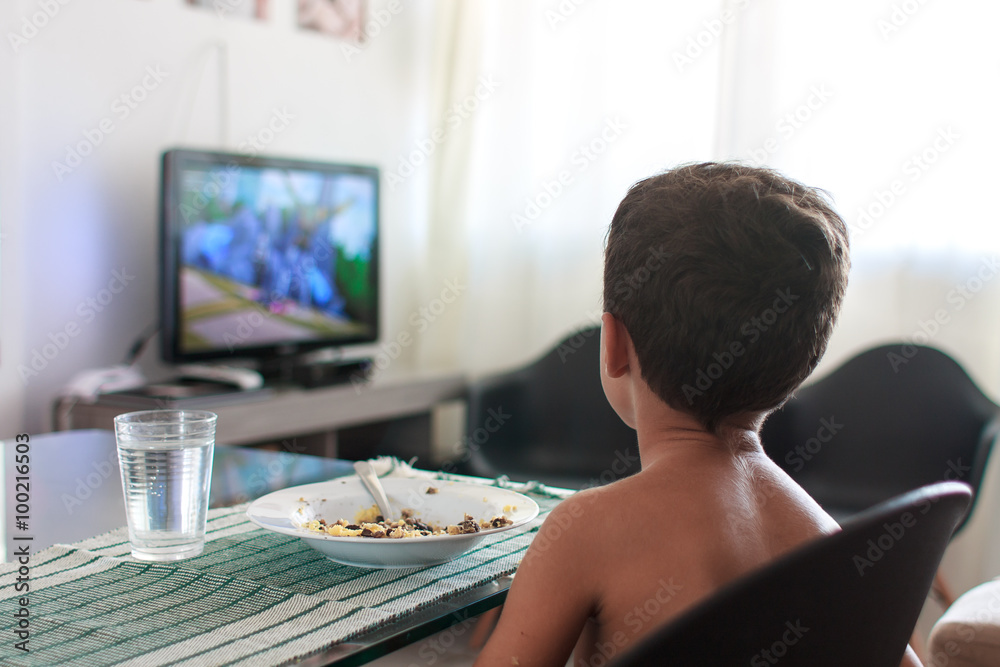 Child distracted watching tv eating lunch Stock Photo | Adobe Stock