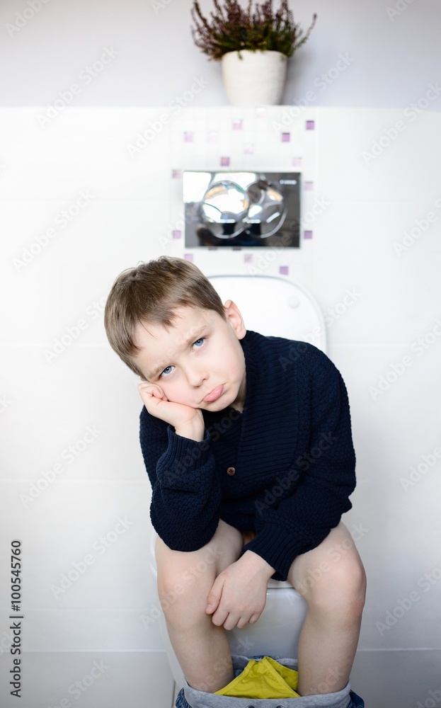 Sad boy sitting on the toilet. Stock Photo | Adobe Stock