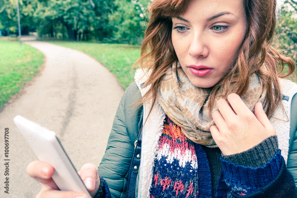 Foto de Young sad beautiful woman texting message on mobile phone in ...