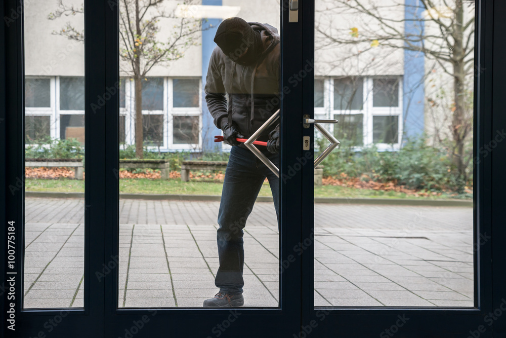 Hooded Man Using Crowbar To Open Glass Door foto de Stock | Adobe Stock