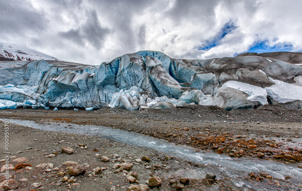 Glacier in Alaska, close up with blue ice and a stream of melted water ...