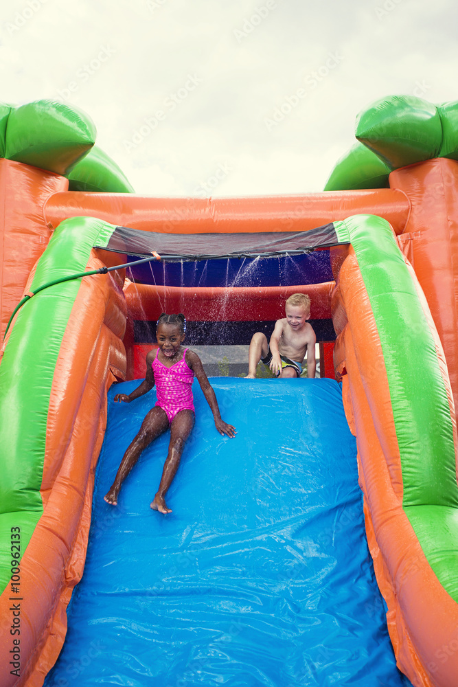 Photo Happy smiling children playing on an inflatable slide bounce ...