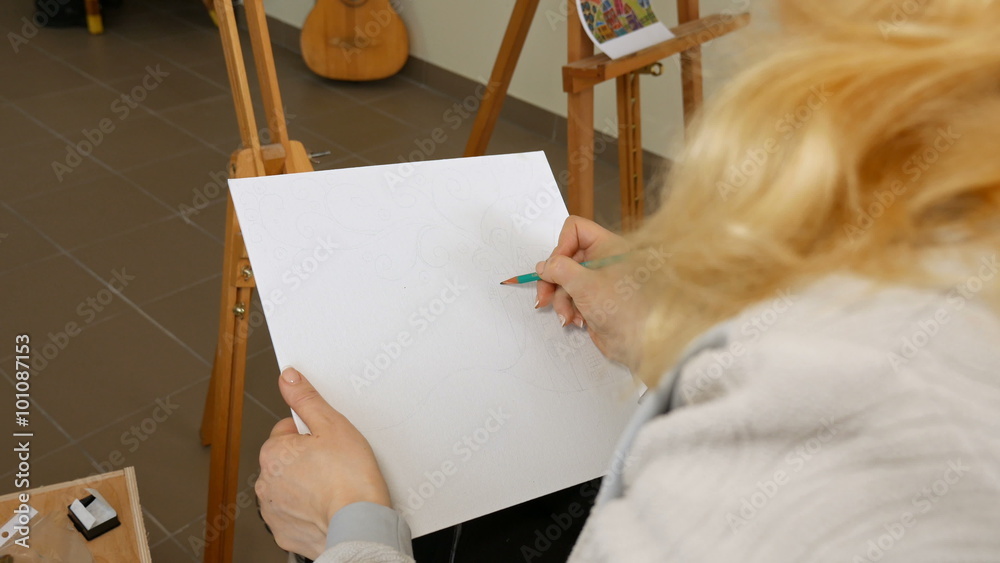 Female artist draws a pencil sketch drawing on canvas easel in art ...