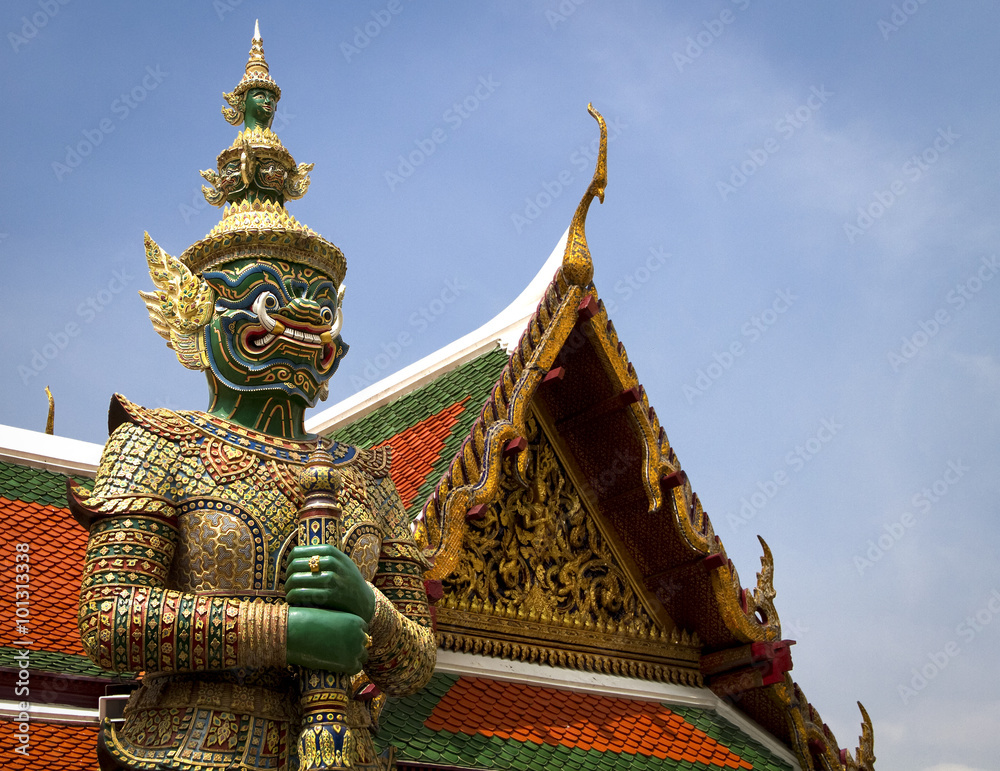 Decorative and colorful monkey guard standing next to Thai style façade ...
