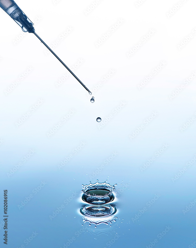 The syringe needle on the blue water background with splash and drops ...