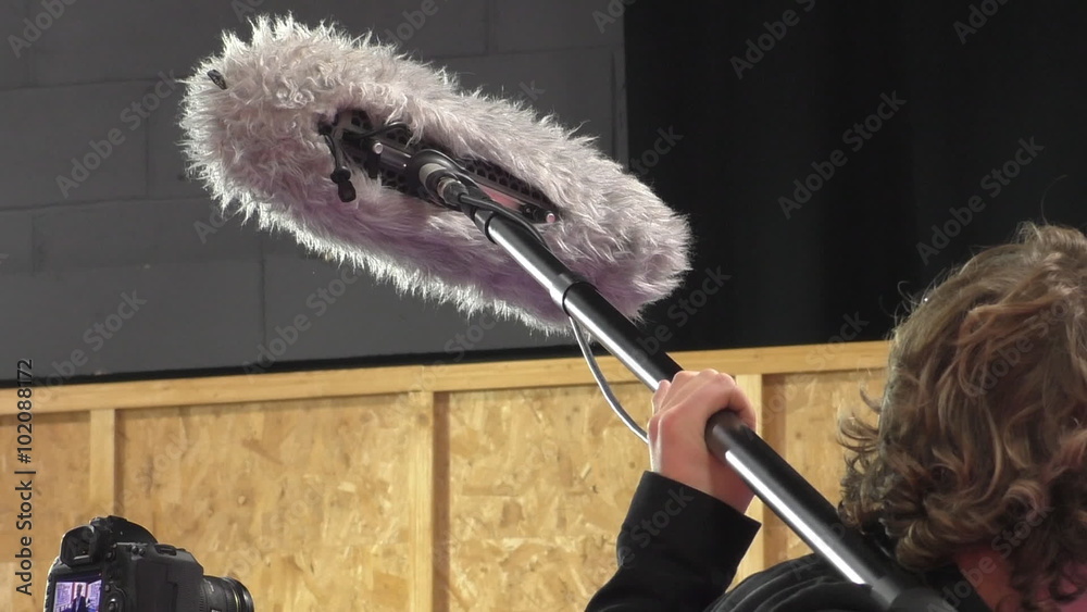 Close up of professional boom operator holding microphone on pole while ...