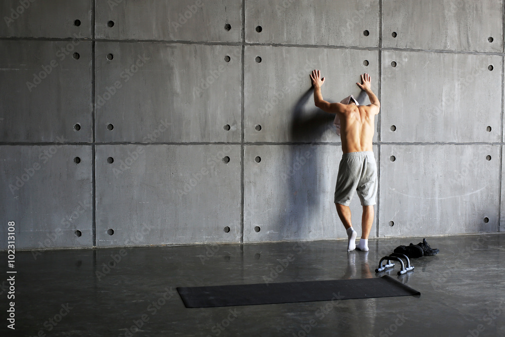 Man at the wall in the gym resting after exercise Stock Photo | Adobe Stock