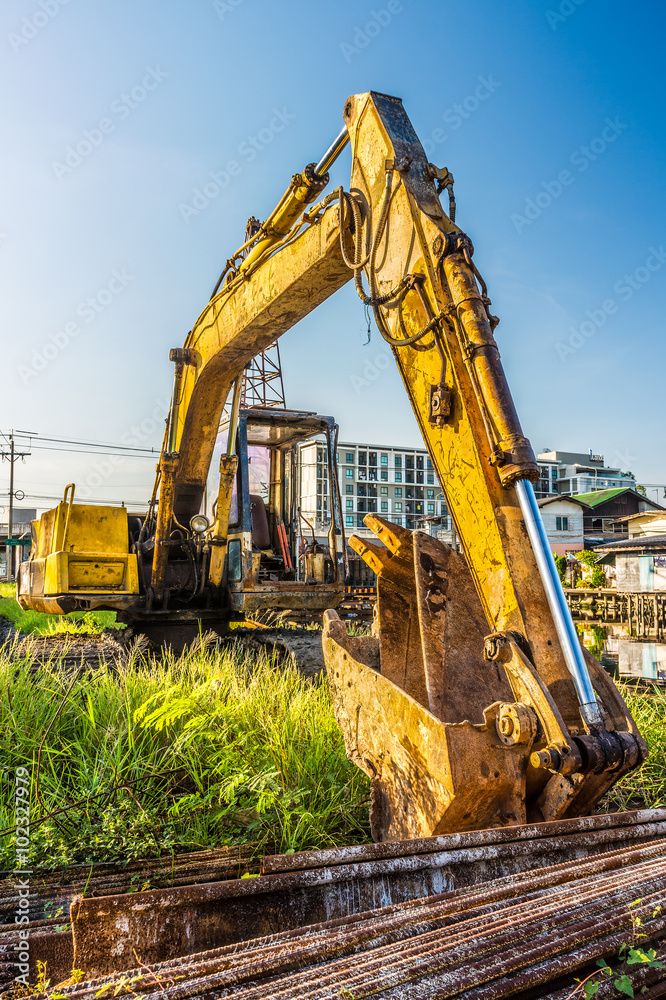 Old backhoe and steel rods at construction site. Backhoe is also called ...
