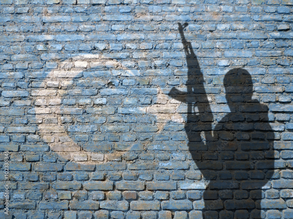 Islamic symbol on wall with shadow of man holding gun Stock ...