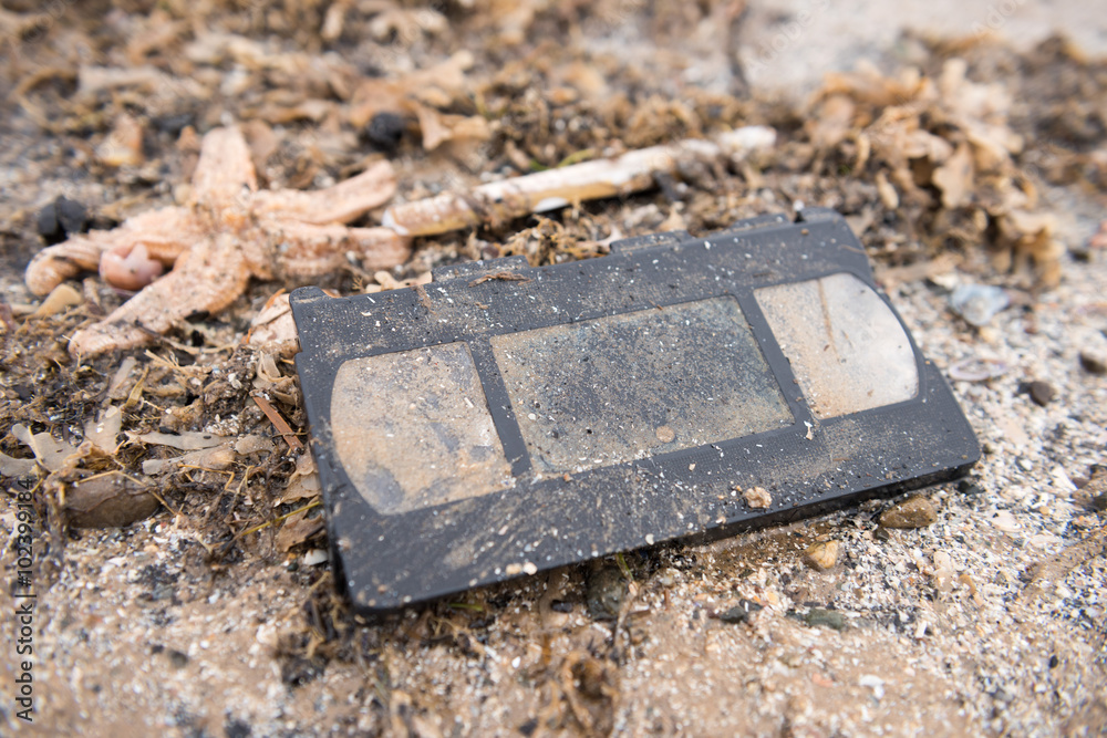 Old retro vas tape washed up on a beach, surrounded by seaweed with a ...