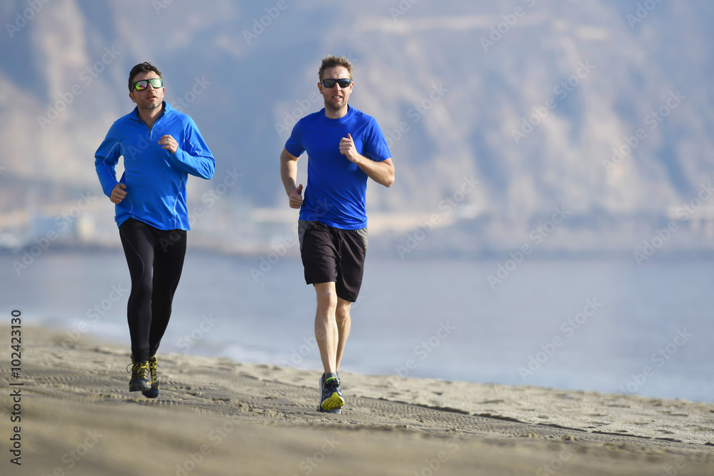 two men friends running together on beach sand coast mountain ba Stock ...