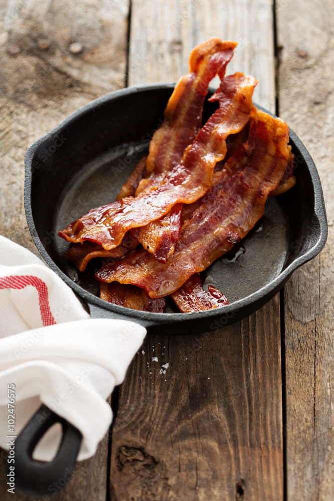 Foto de Sizzling hot bacon in a cast iron skillet do Stock | Adobe Stock